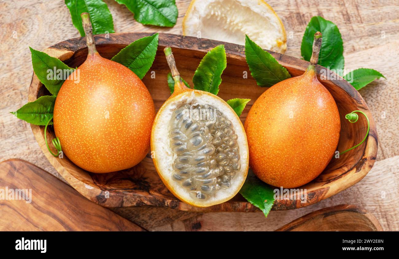 Granadilla fruits with leaves on wooden table. Top view Stock Photo - Alamy