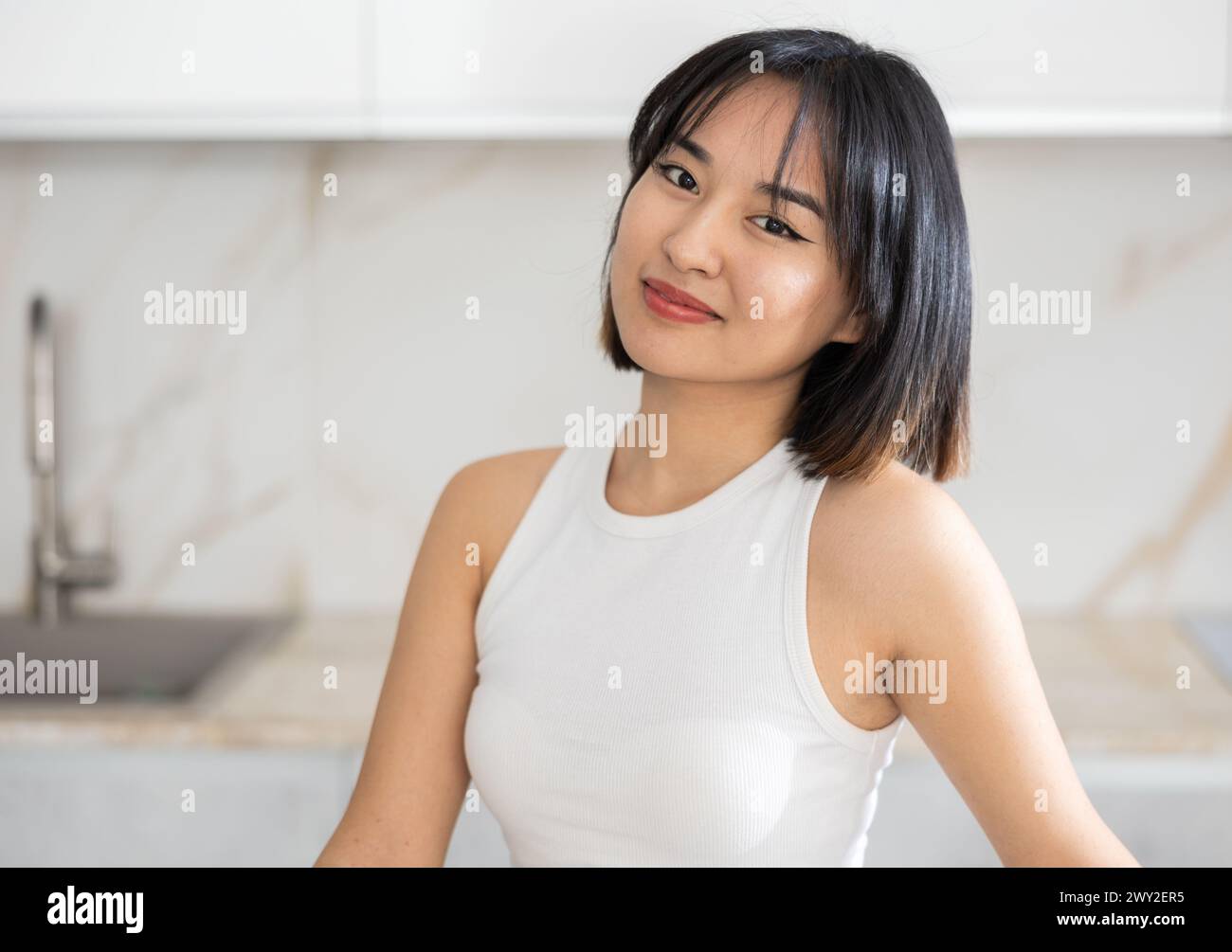 Smiling young Asian girl standing at table in the kitchen Stock Photo ...