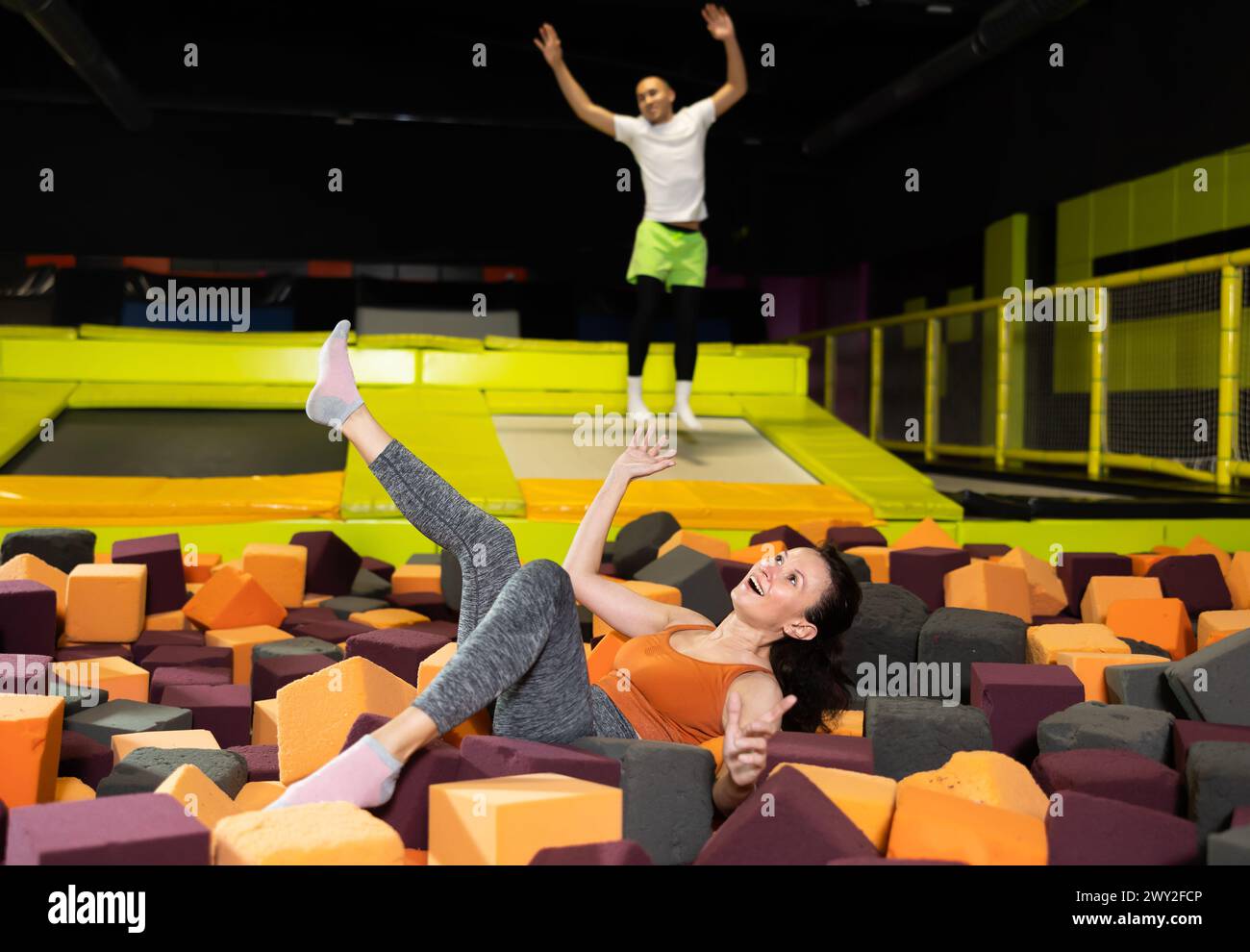 Woman laughing while landing in foam pit at trampoline park Stock Photo ...