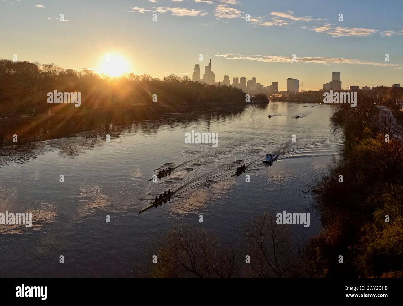 Crews row north on the Schuylkill River as the sun rises behind the ...