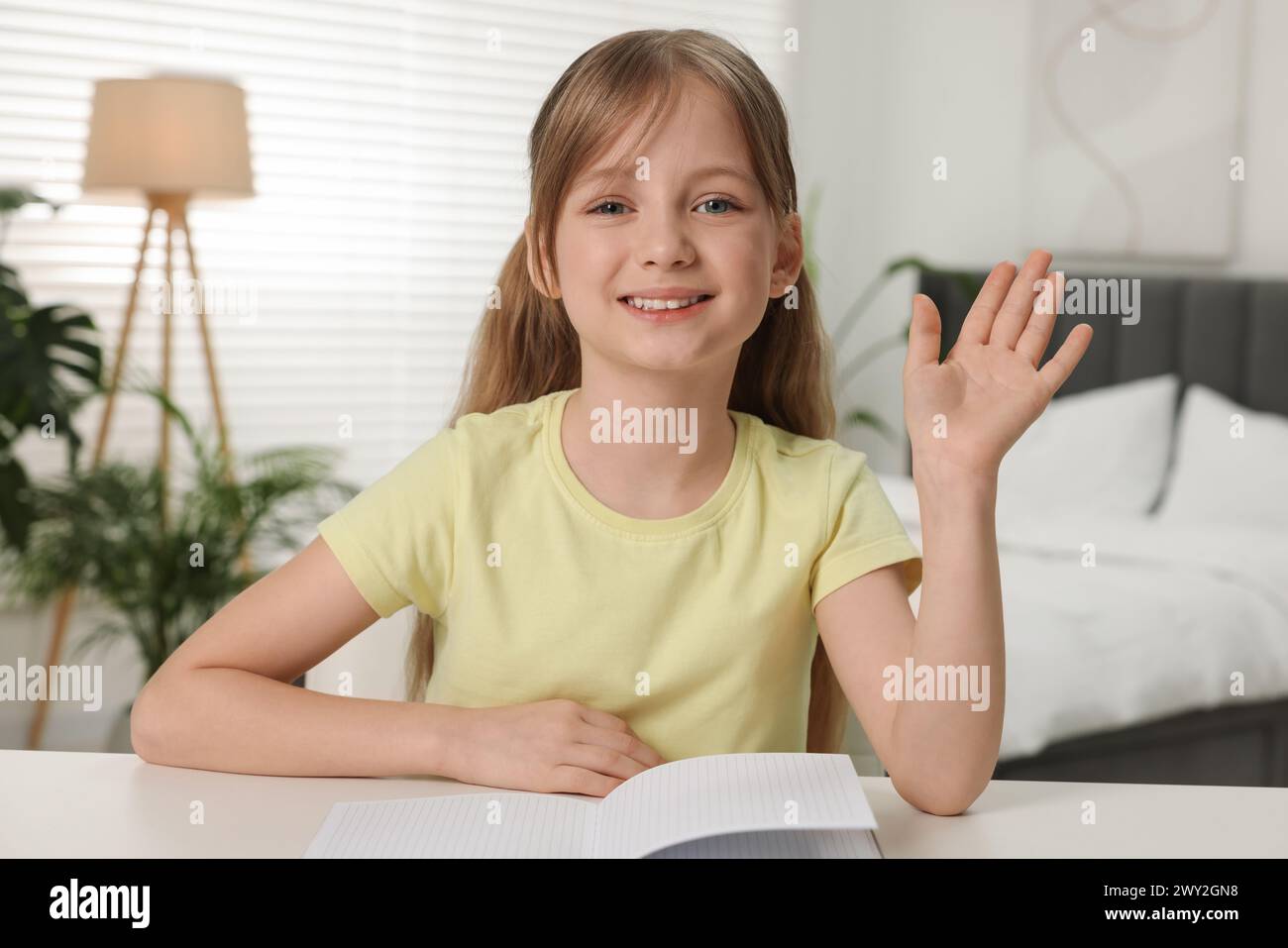 Happy little girl waving hello during online lesson indoors, view from ...