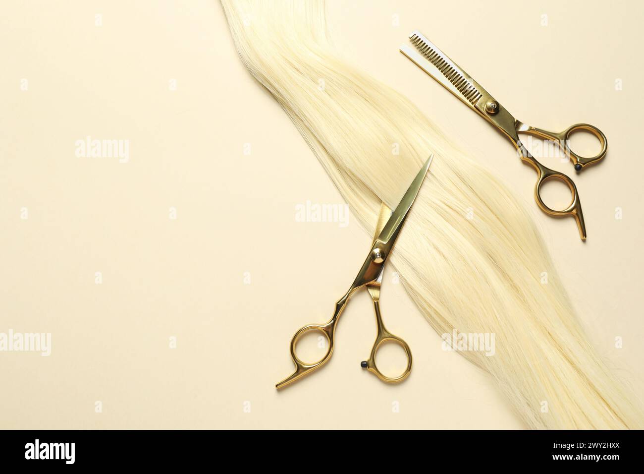 Professional scissors with blonde hair strand on beige background, flat ...