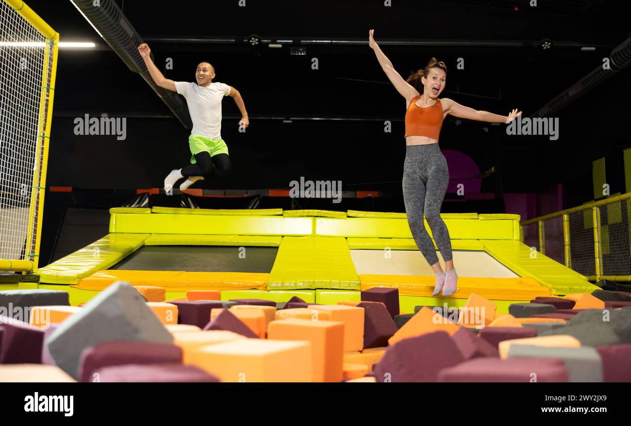 Happy athletes, man and girl, training to jump on trampolines at ...