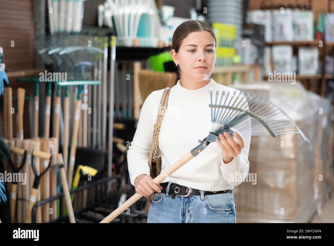 Girl carefully chooses rake in hardware store to clean garden Stock ...