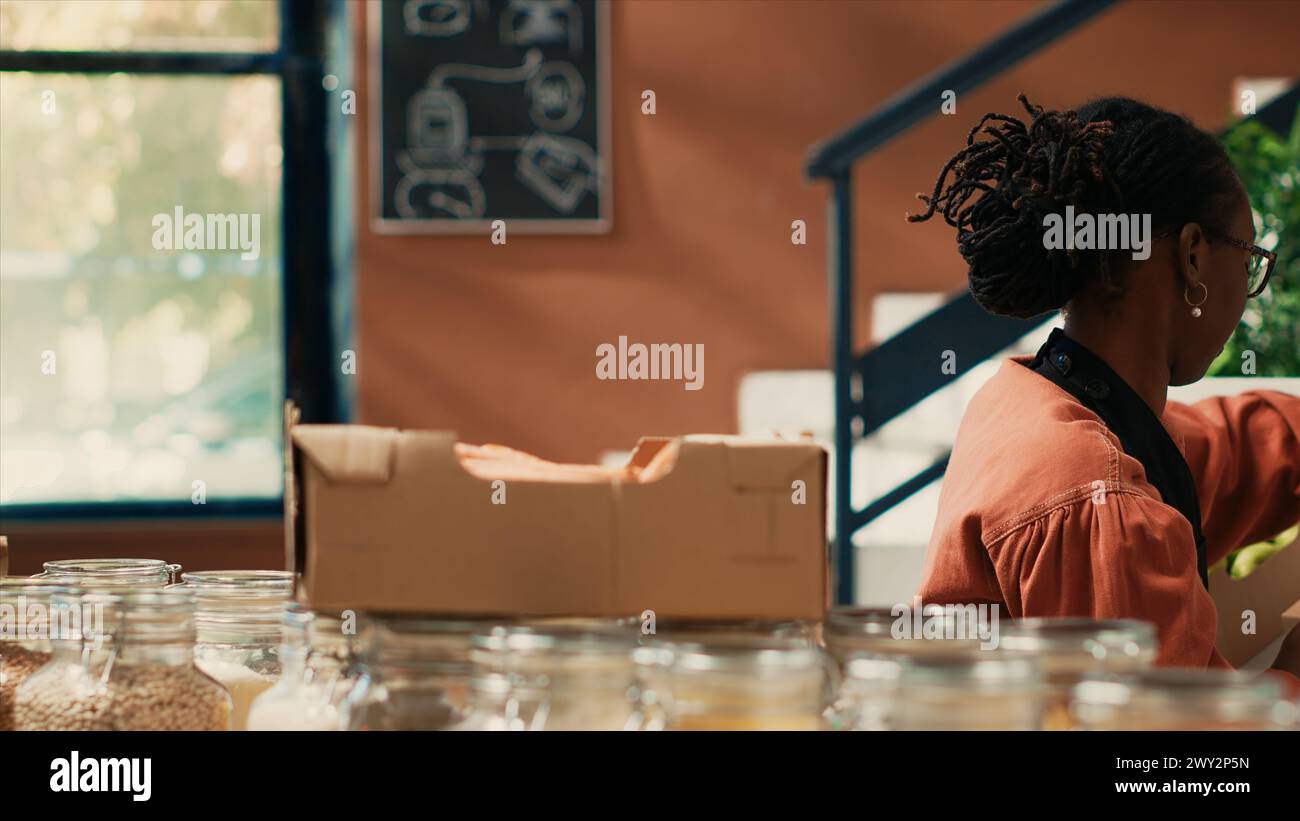 Vendor placing crates of fruits and veggies on shelves after organic ...