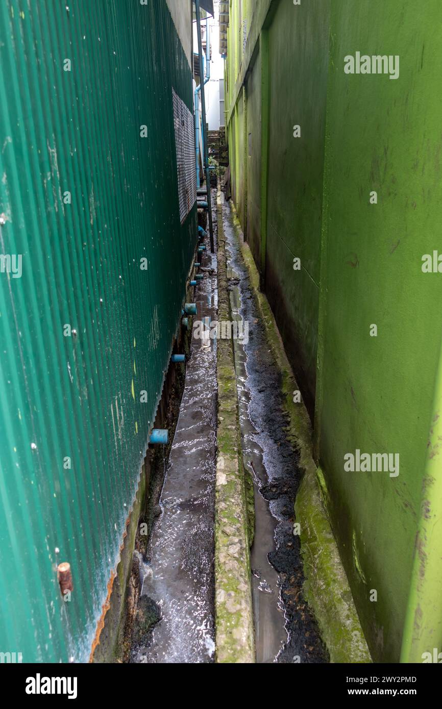 Sewage drain - outflow between houses on city street Stock Photo - Alamy