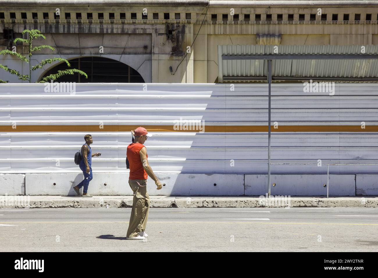Cuban people walking by metal fence on a construction site, Havana ...