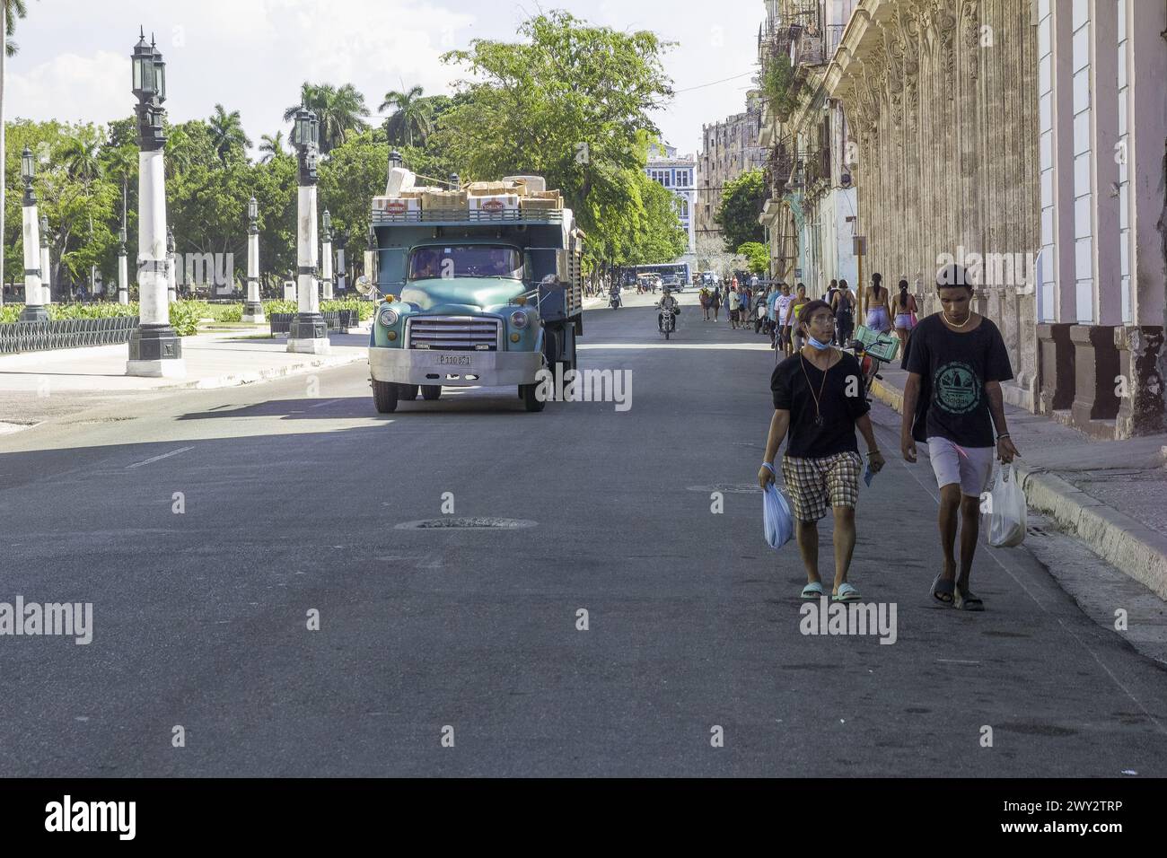 Cuban people walking in the downtown district, old truck driving ...