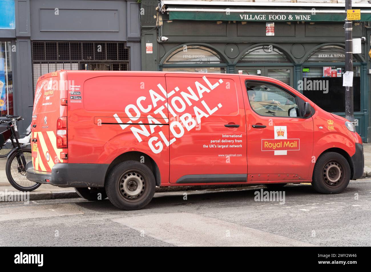 Side view of royal mail delivery van parks outside shop delivering ...