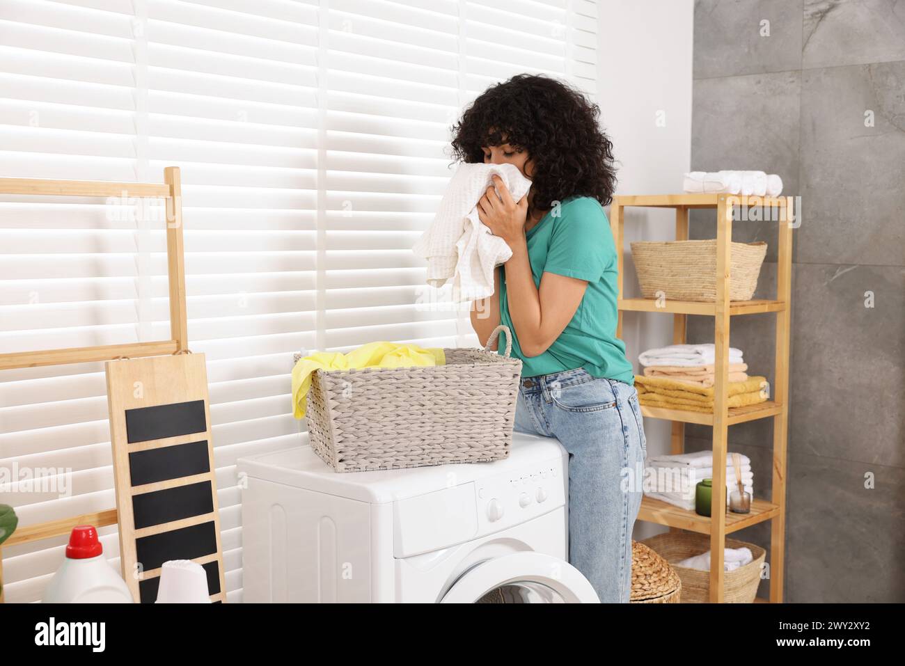 Woman with clean laundry near washing machine indoors Stock Photo - Alamy