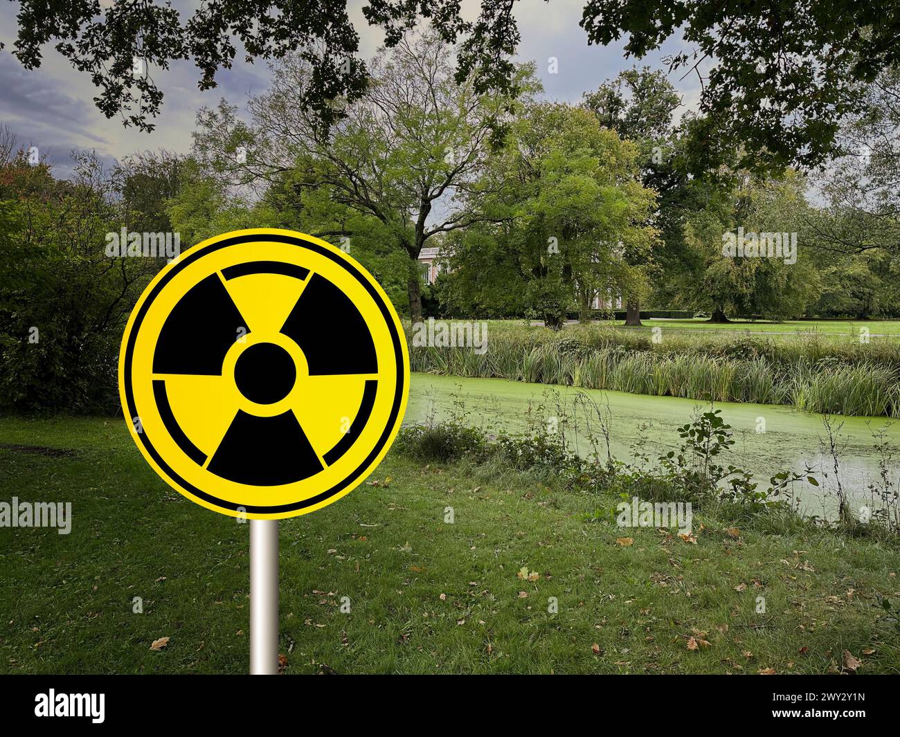 Radioactive pollution. Yellow warning sign with hazard symbol in rural ...