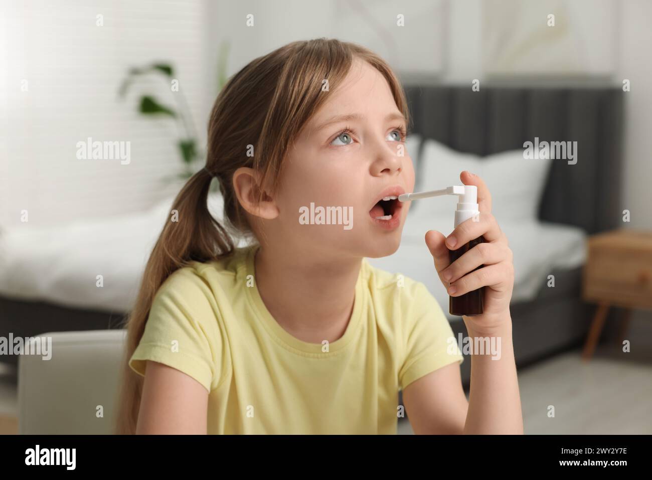 Little girl using throat spray at home Stock Photo - Alamy