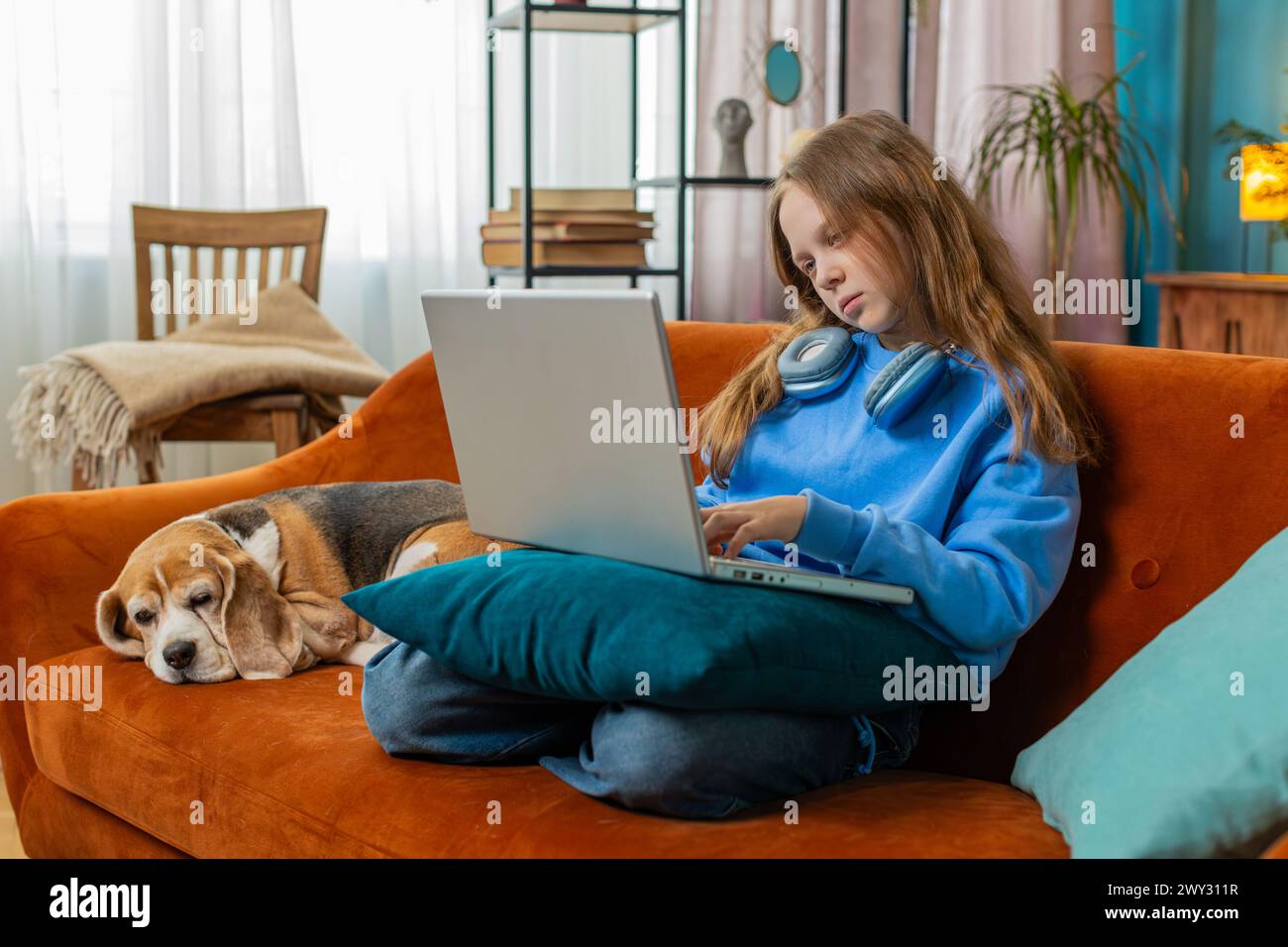 Overtired Caucasian girl bored using laptop while sitting on sofa near ...