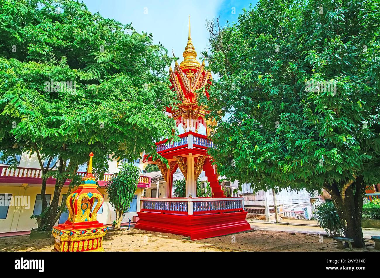 The bright red Ho Rakang belfry of Wat Suwan Kuha Cave Temple between ...