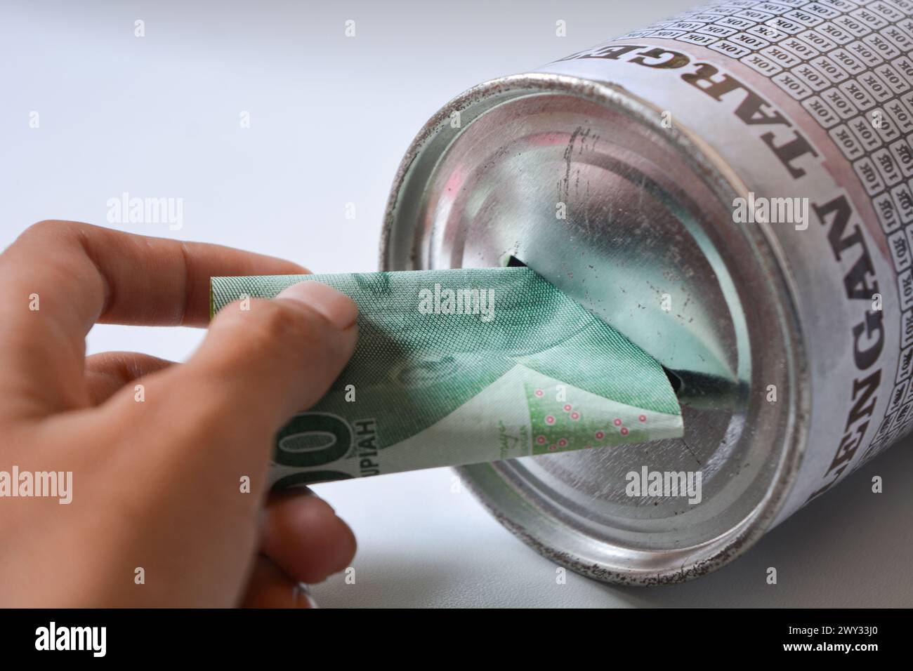 Hand putting Indonesian rupiah money into traditional Indonesian white ...