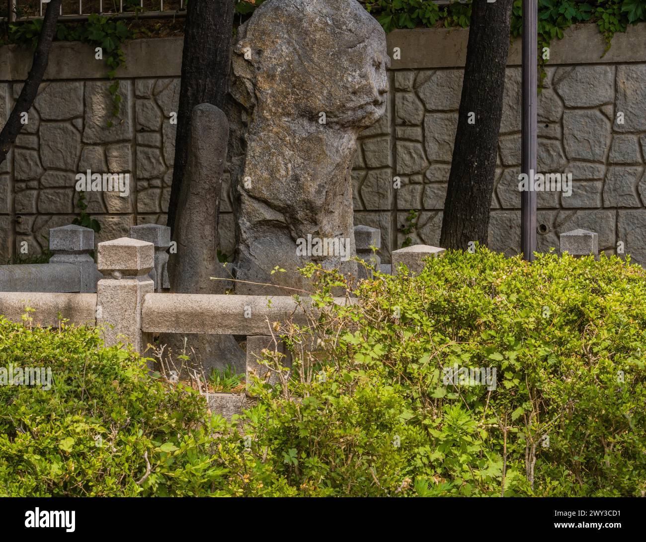 Stone totem with Chinese symbols protected with concrete fence sitting ...