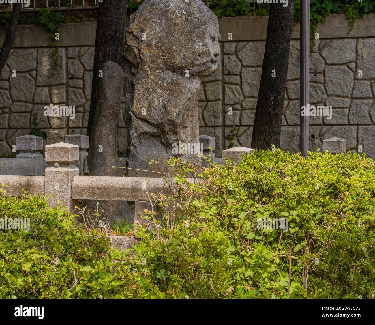 Stone totem with Chinese symbols protected with concrete fence sitting ...