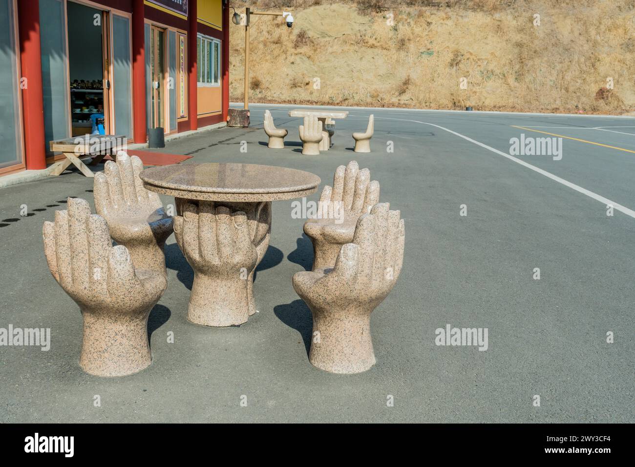 Marble table and chairs in shape of hands in front of temple building ...