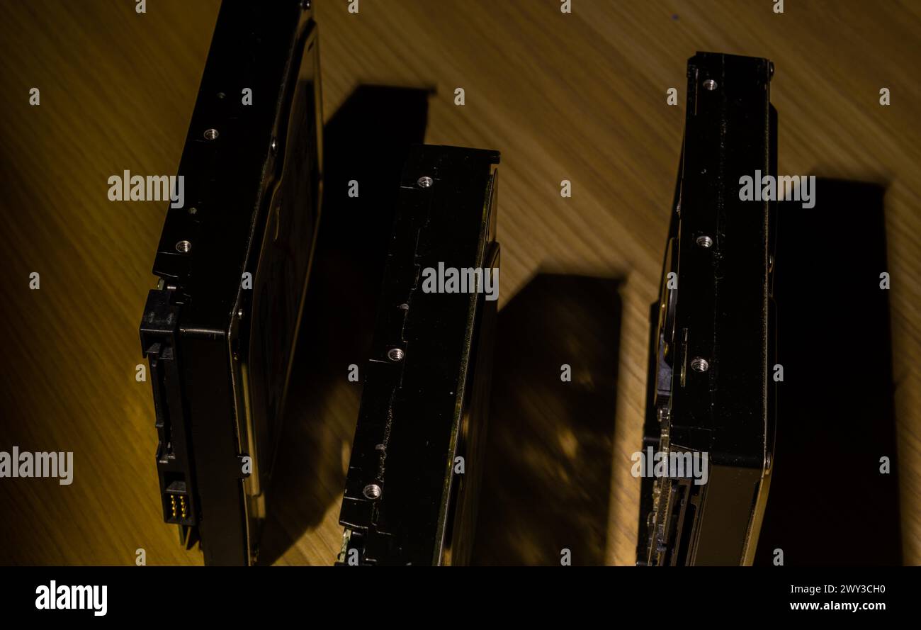Three desktop computer hard disk drives on wooden workbench in soft ...