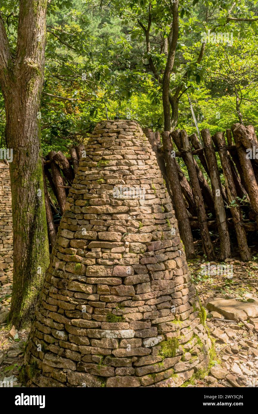Tall cairn (stack of stones) under shade trees in woodland park in ...