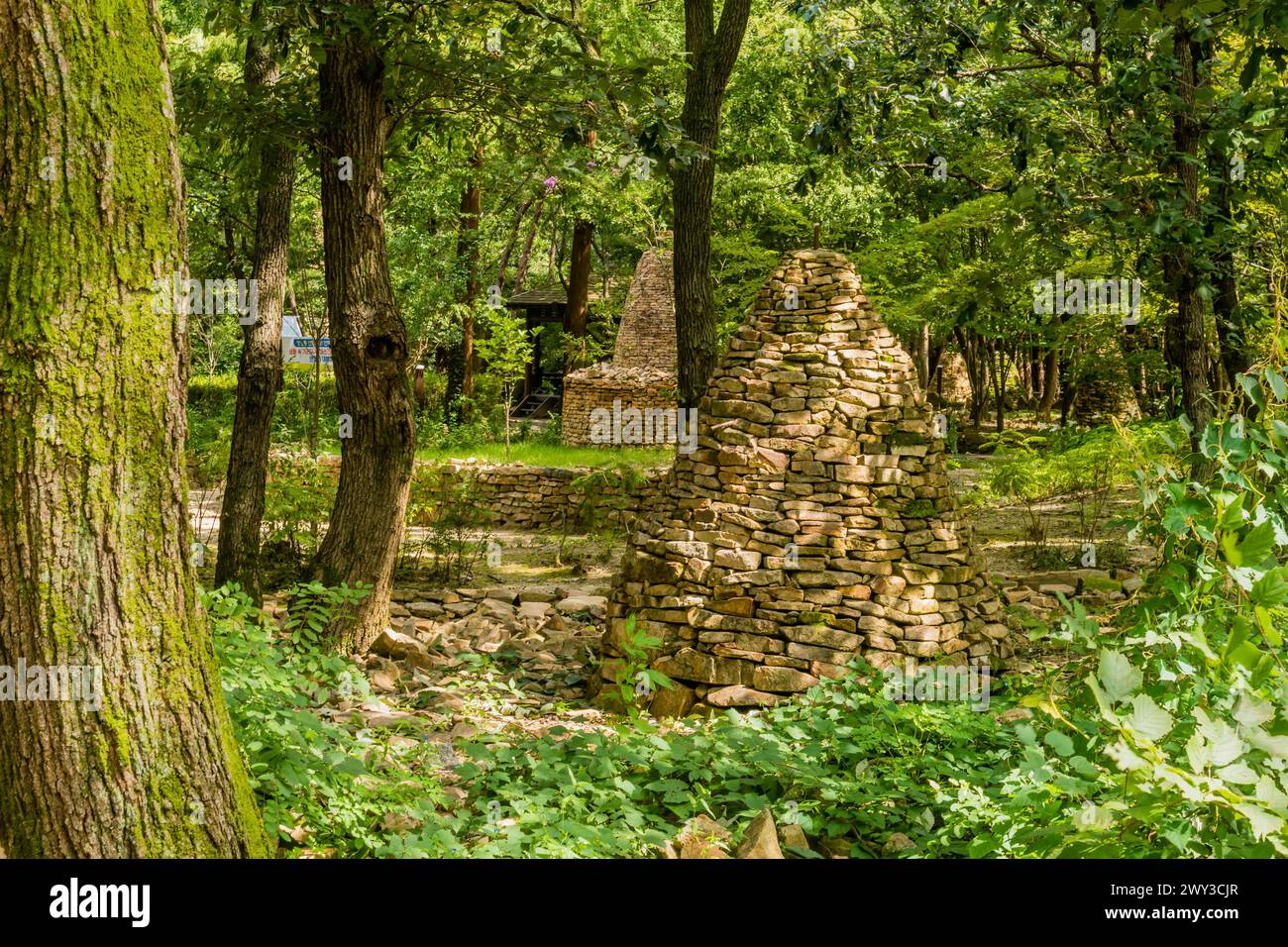Tall cairn (stack of stones) under shade trees in woodland park in ...