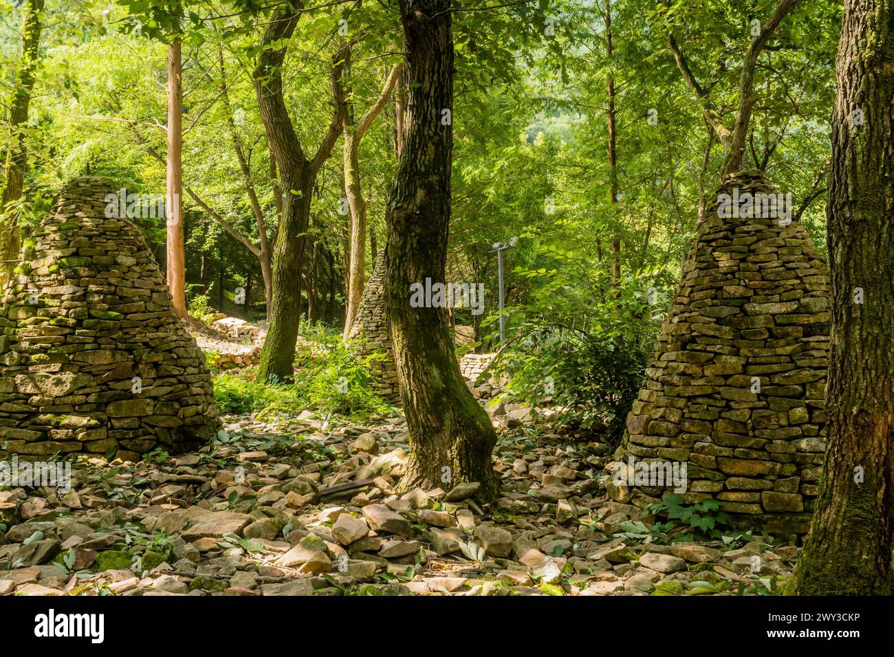 Tall cairns (stack of stones) under shade trees in woodland park in ...