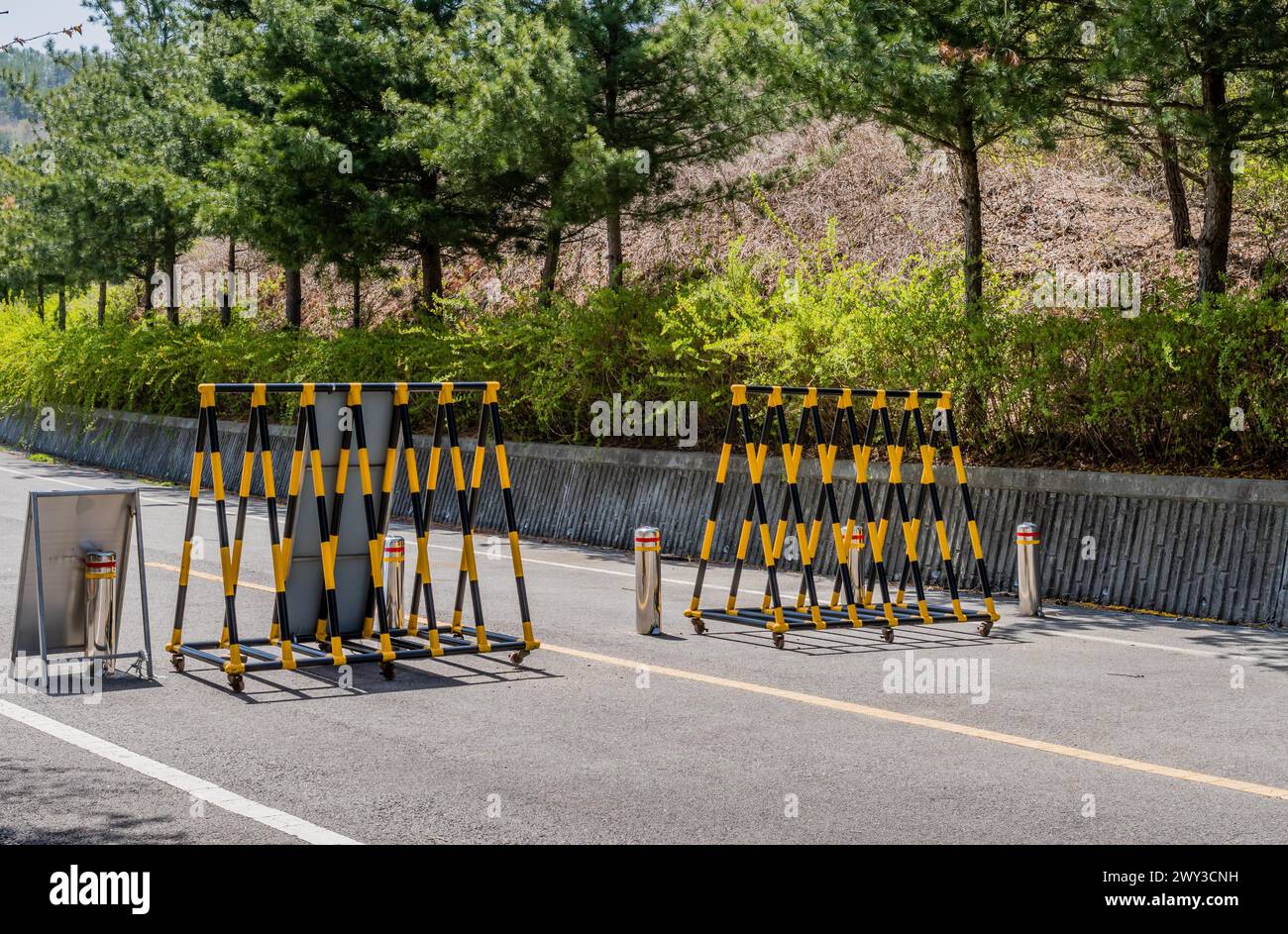 Two Yellow and black traffic barrier blocking paved road in woodland ...