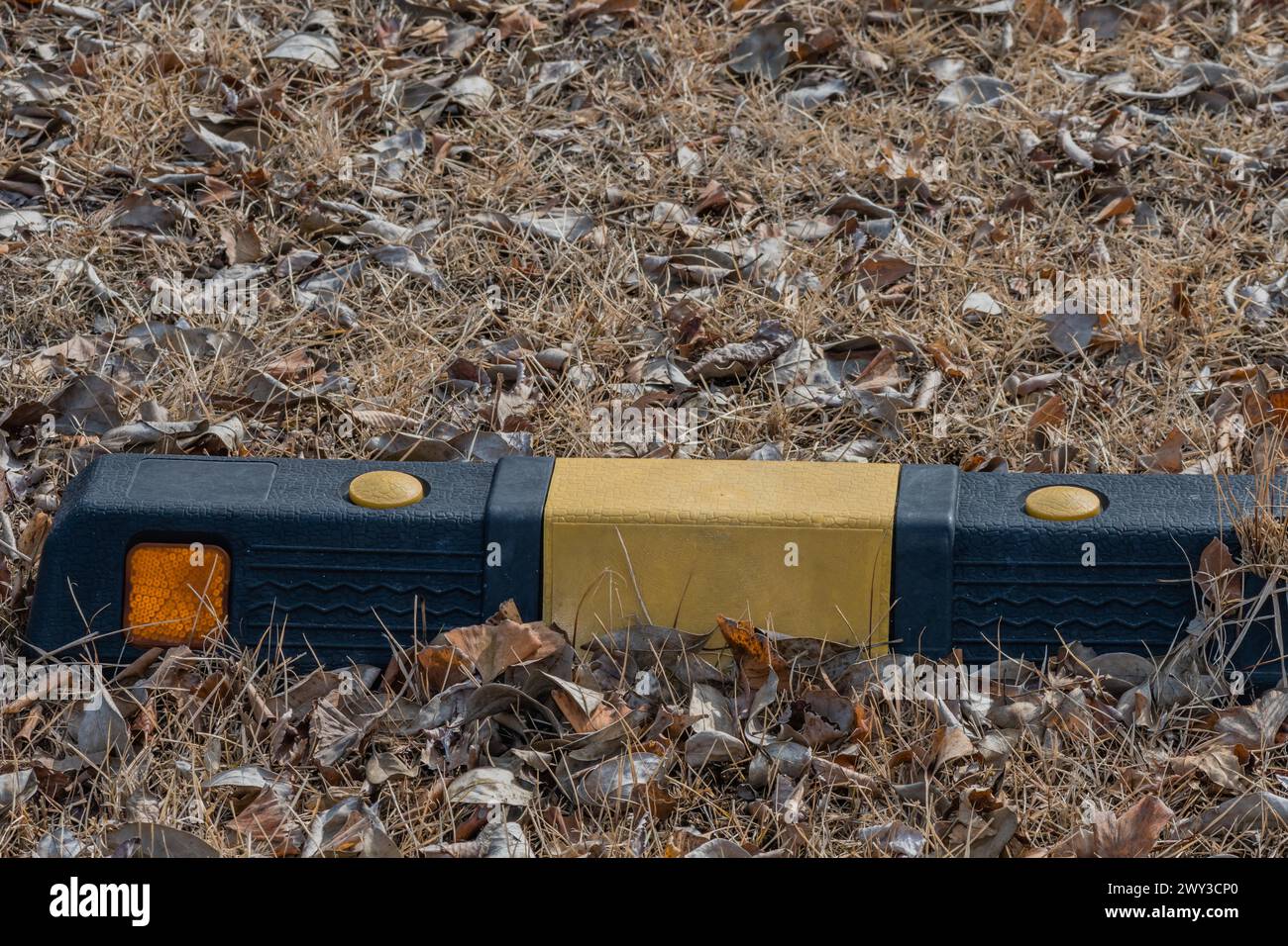 Closeup of yellow and black wheel stops in dry grass parking area in ...