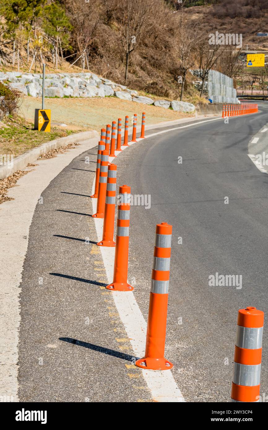 Traffic bollards mounted on white line on side of curvy rural road in ...