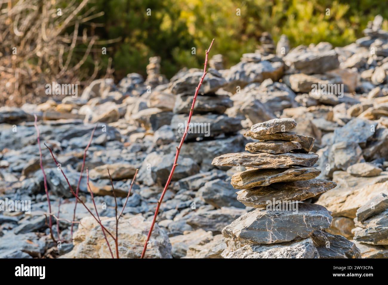 Closeup of stack of flat rocks with other stack of rocks blurred out in ...