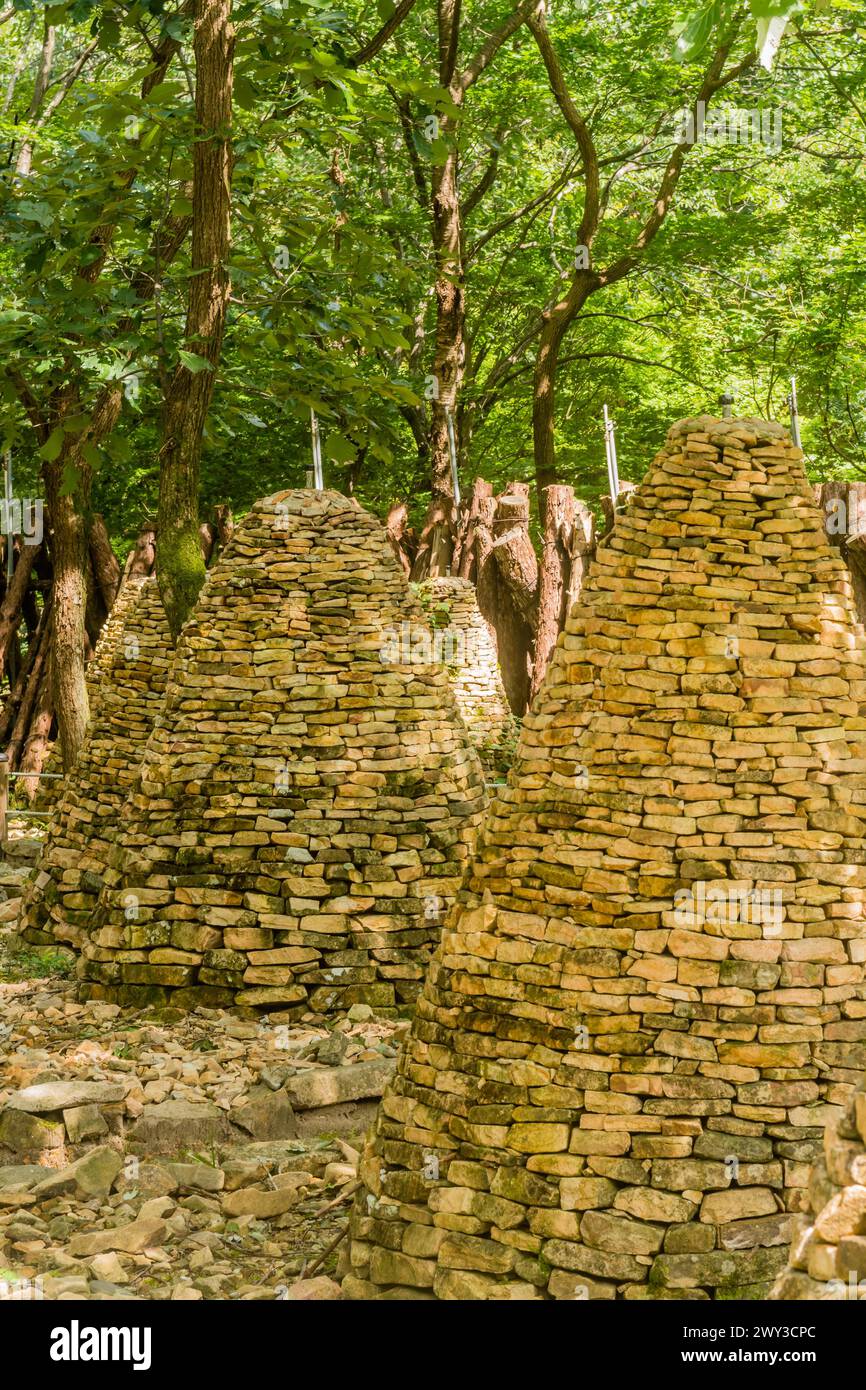 Row of cairns (stacks of stones) under shade trees in woodland park in ...
