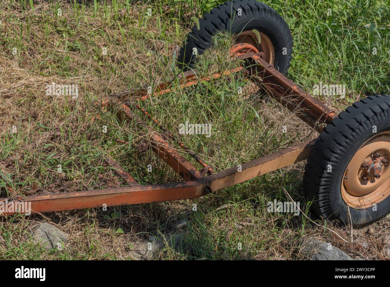 Rusty trailer frame and wheel assembly sitting in high grass in South ...