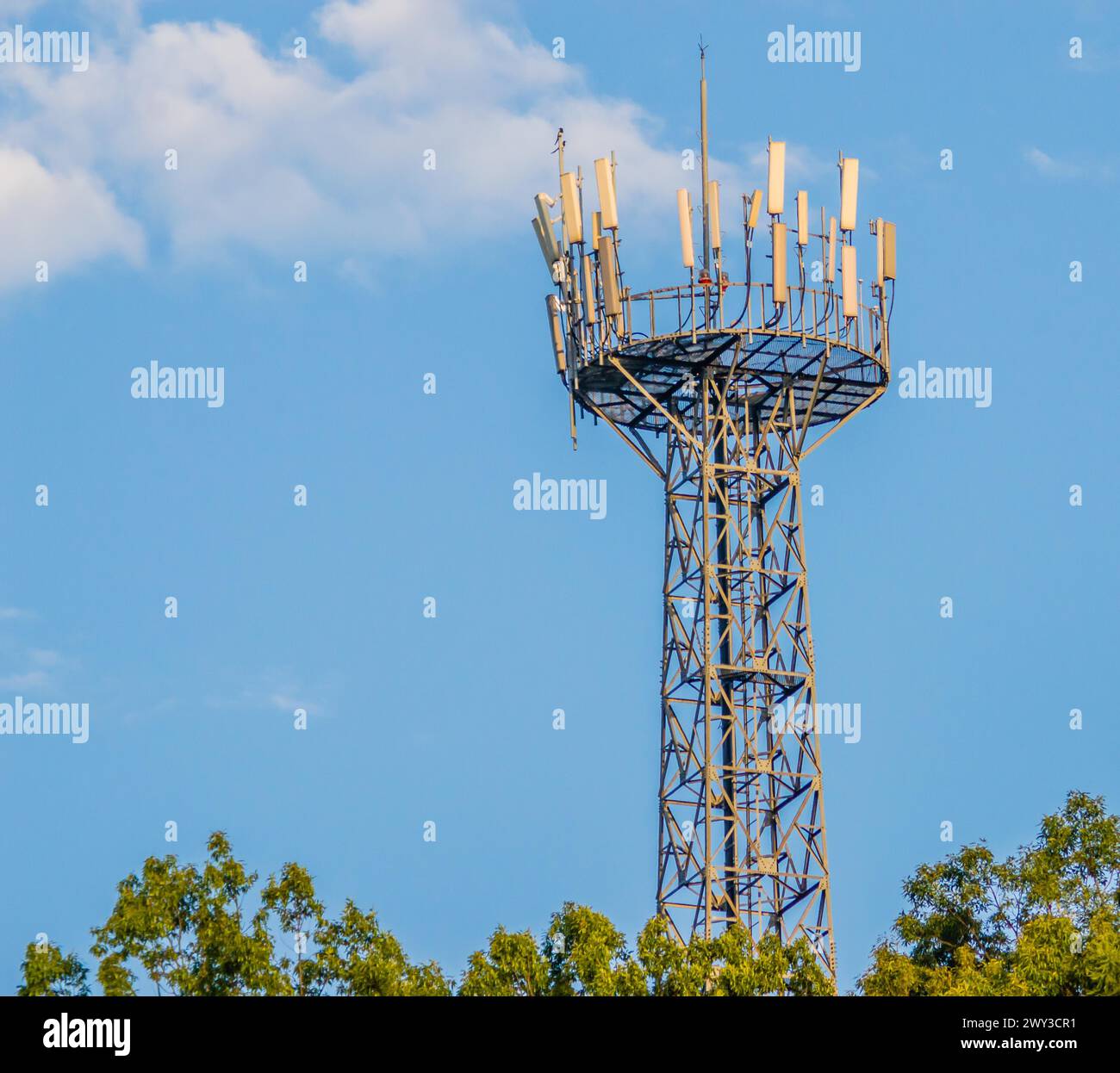 A tall communication tower stands prominently against a clear blue sky ...
