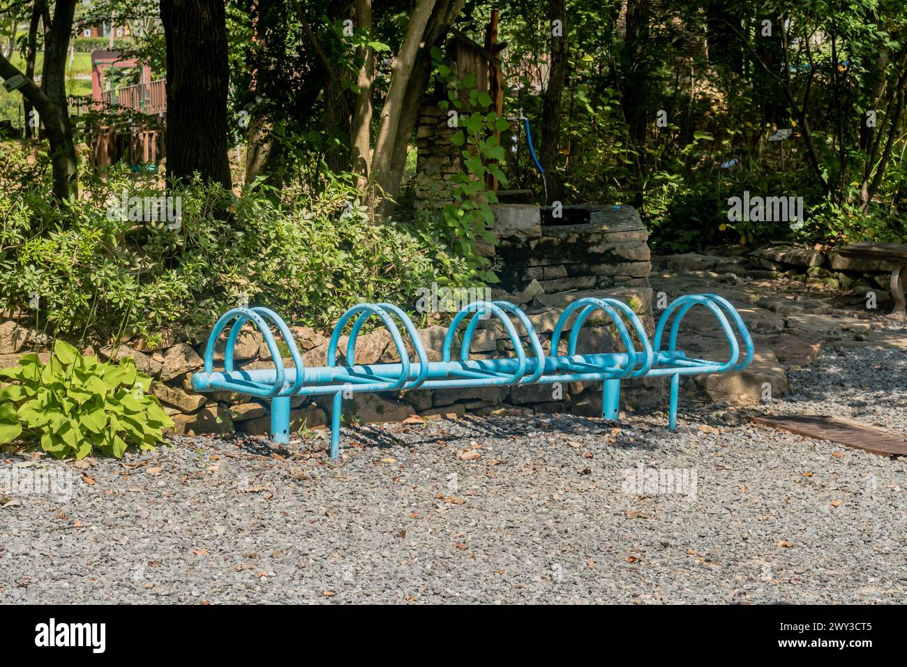 Blue metal bike rack in gravel lot in front of trees in recreational ...