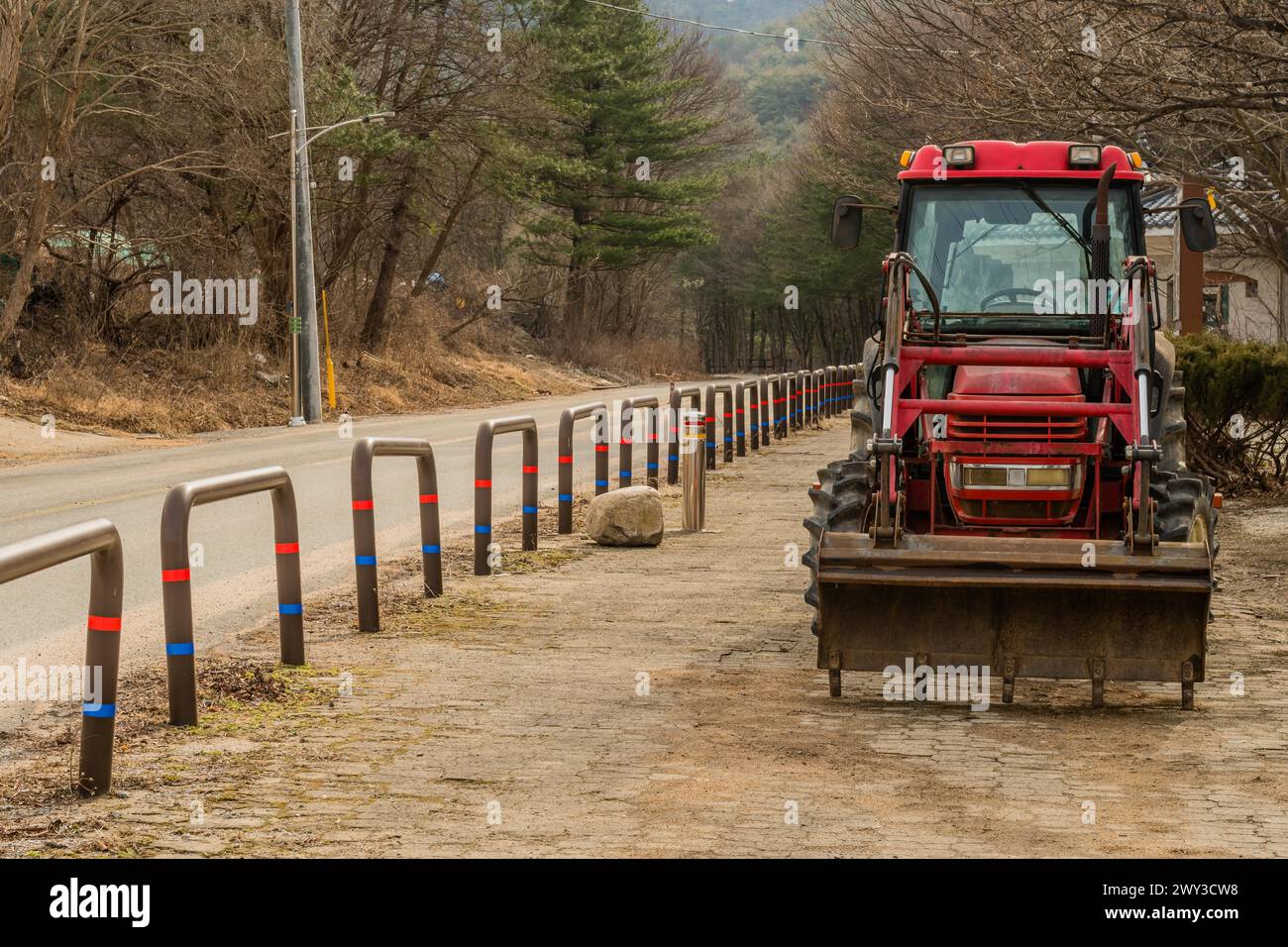 Red tractor park in South Korea.ed on sidewalk next to rural road in ...