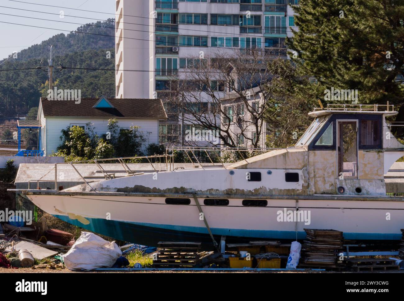 Large boat in a state of disrepair in dry dock with buildings and trees ...