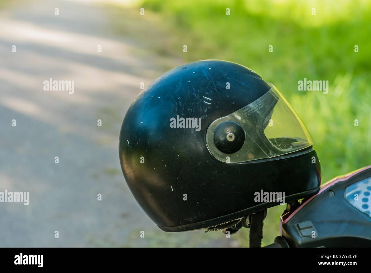 Black motorcycle helmet resting on handlebar of scooter with blurred ...