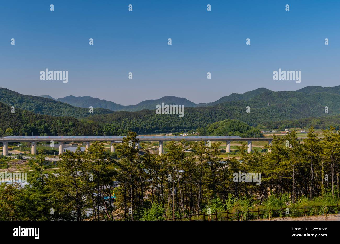 High speed train speeding across concrete railroad bridge in rural ...