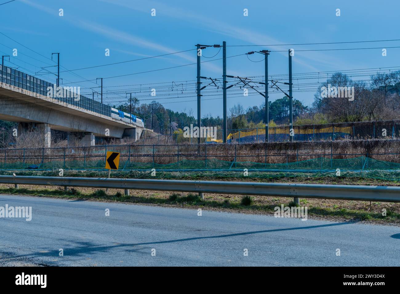 Rural landscape of train crossing concrete overpass with electrical ...