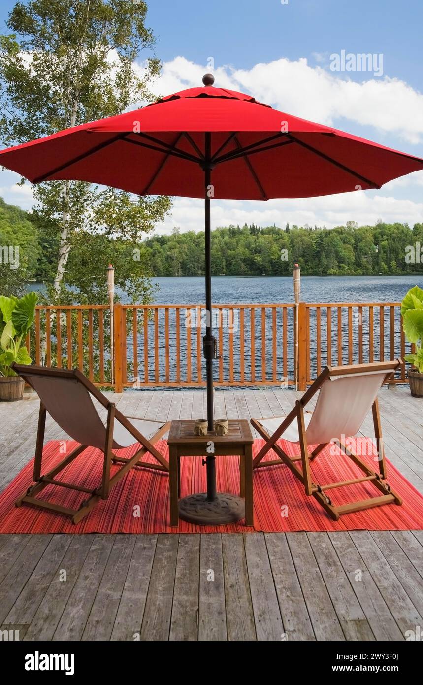 Red canvas cloth parasol and wooden folding canvas chairs on red mat on ...