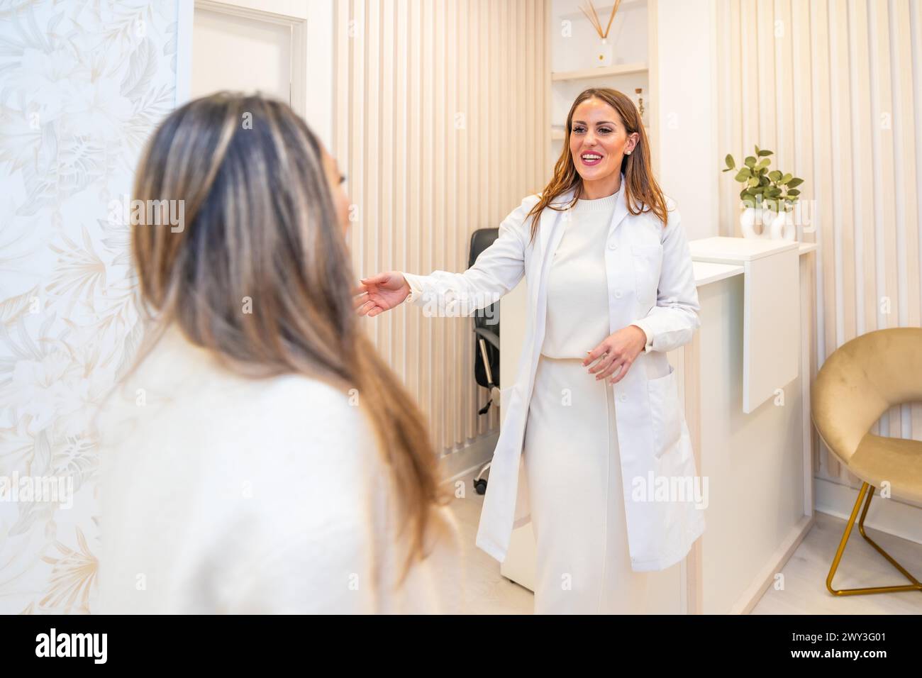 Female aesthetic doctor with lab coat and elegant clothes welcomes a ...