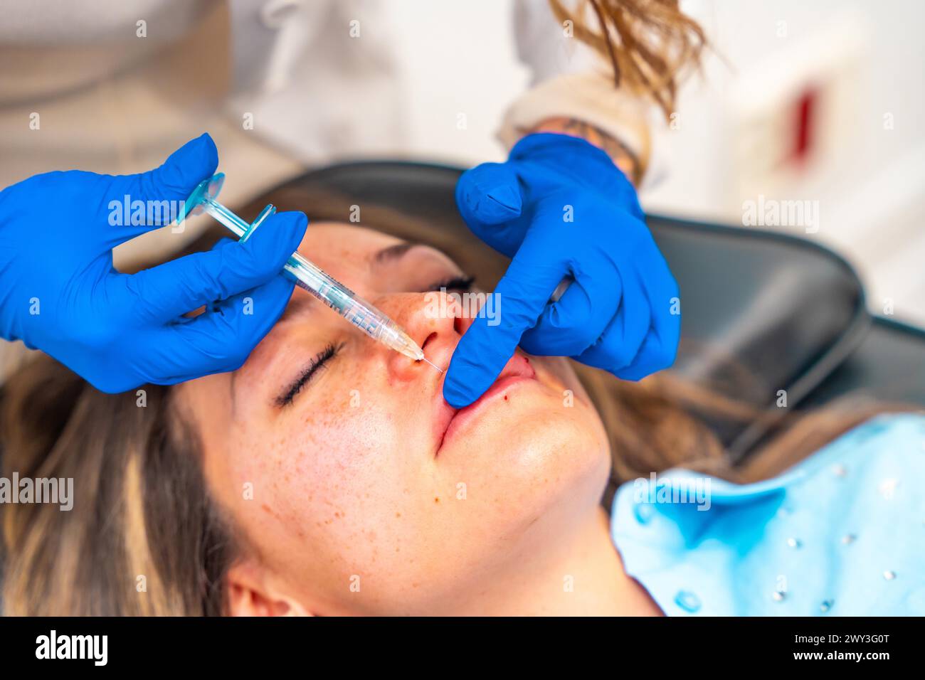 Close-up of the hands of a female doctor applying botox therapy on lips ...
