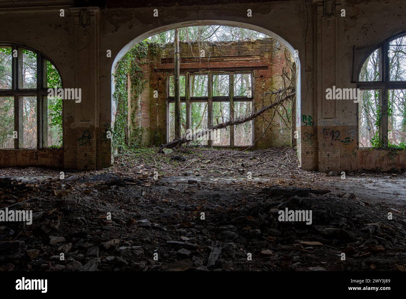 Interior view of a dilapidated building with arched windows and debris ...