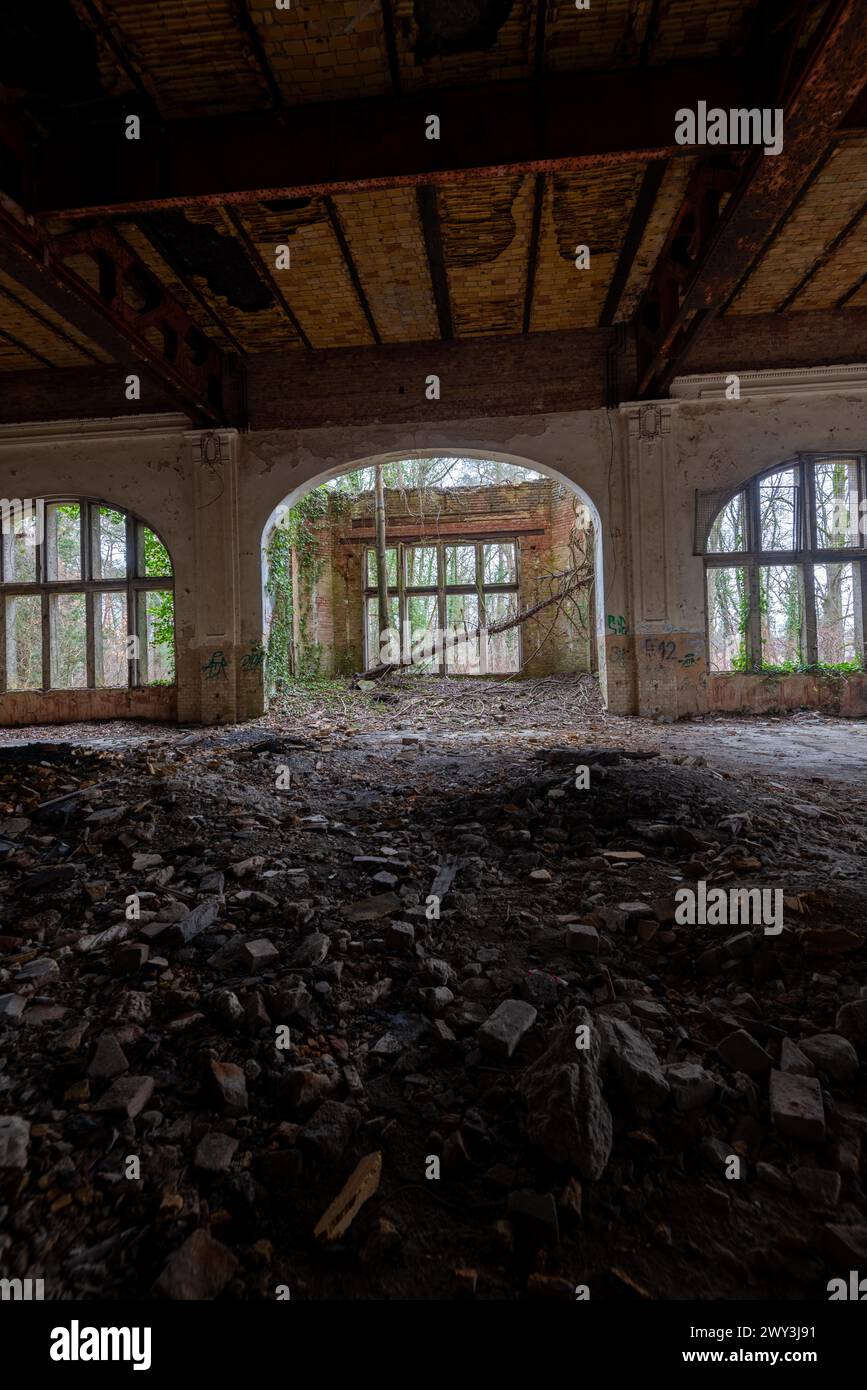 Interior view of a dilapidated building with arched windows and debris ...