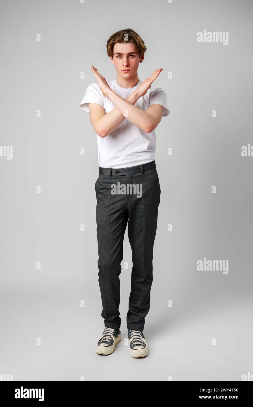 Young Man Making an X Sign With His Arms Against a Gray Background ...