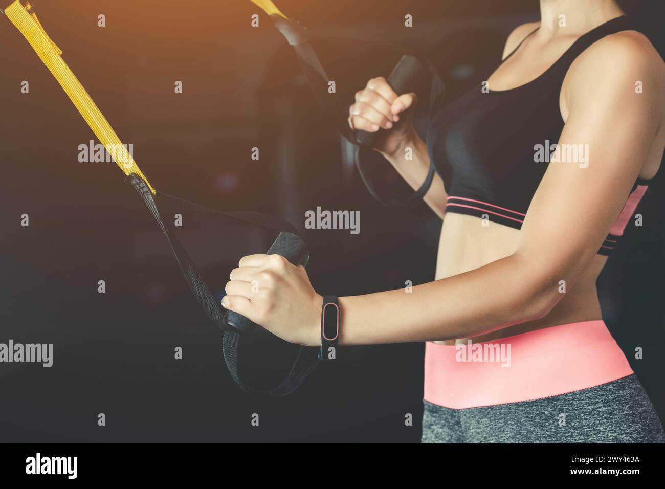 A slender girl holds a strap in her hand for the suspension training in ...