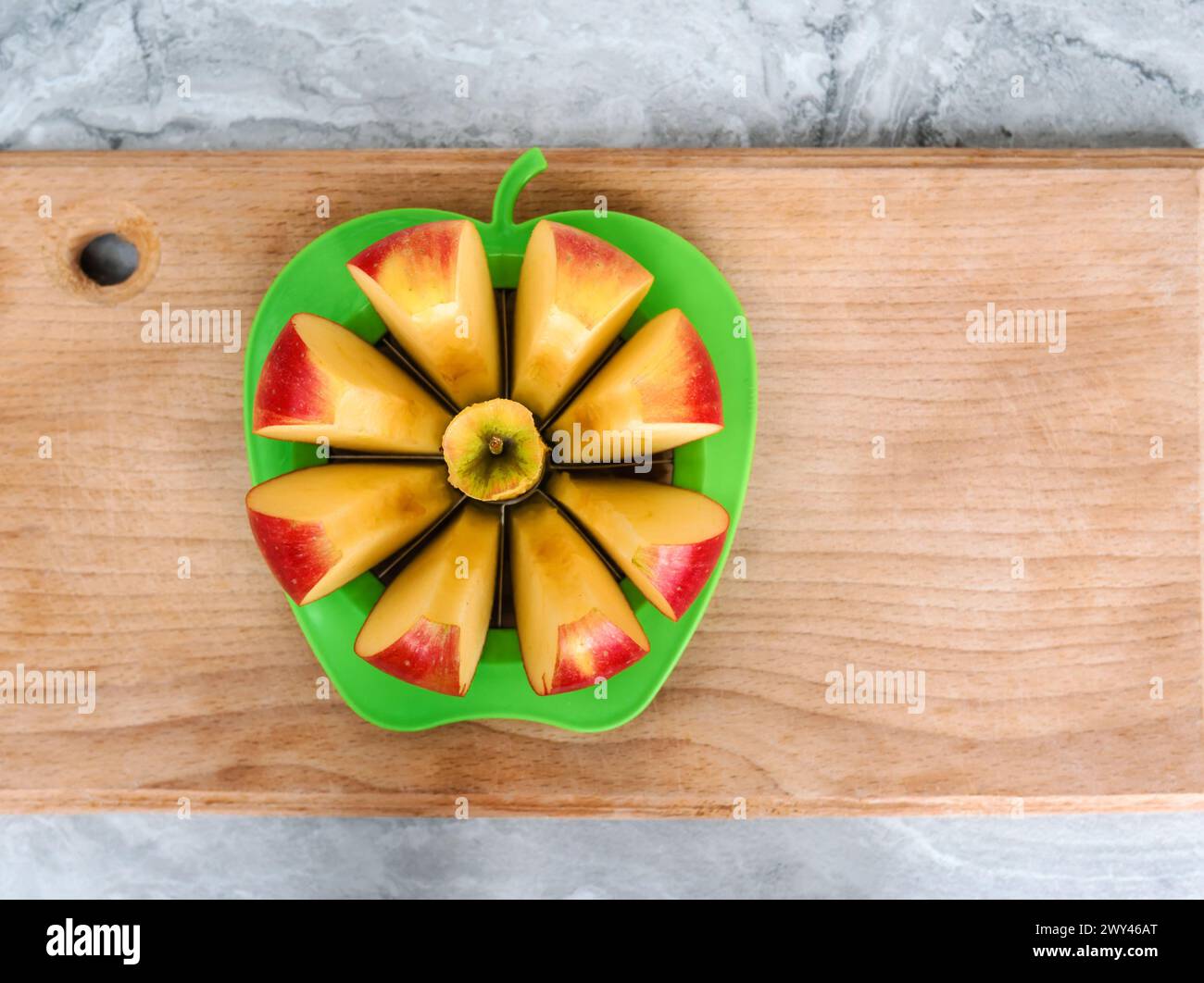 An apple on a cutting board is cut into slices using a special slicer ...