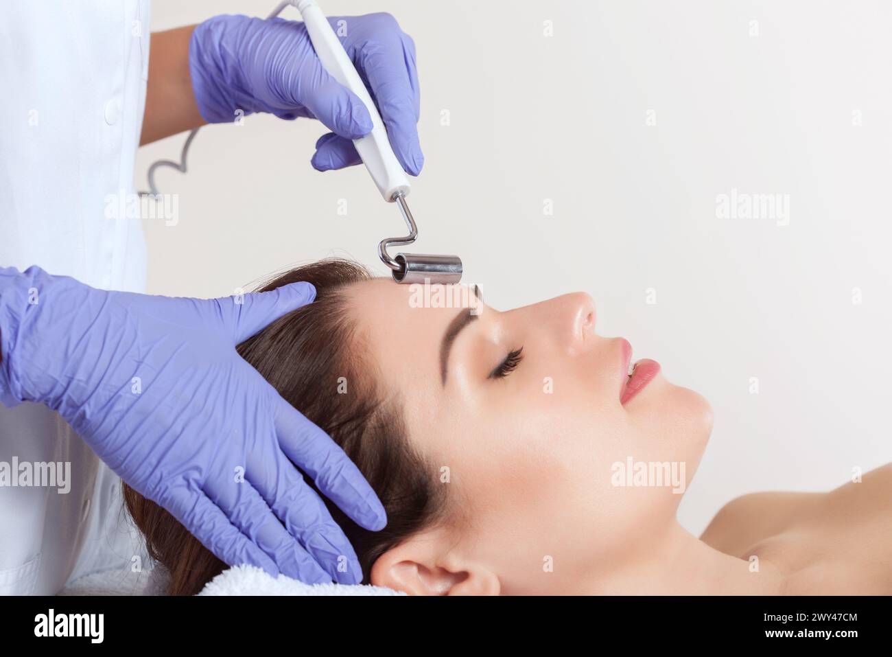 The cosmetologist makes the apparatus a procedure of Microcurrent therapy of a beautiful, young ...
