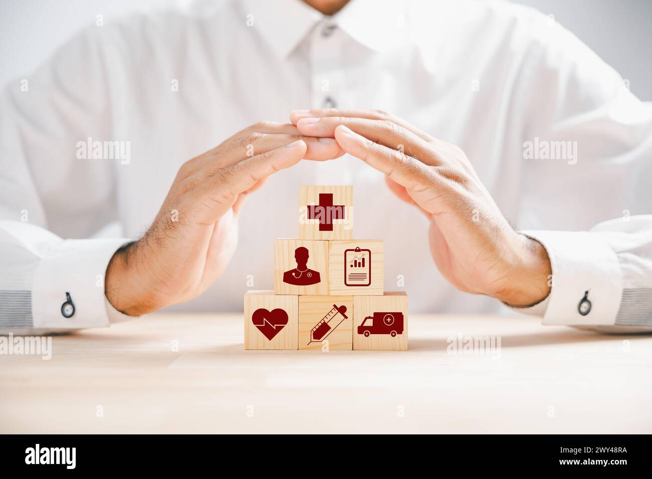 Wooden cube block displaying healthcare icons, topped by a doctor hand ...