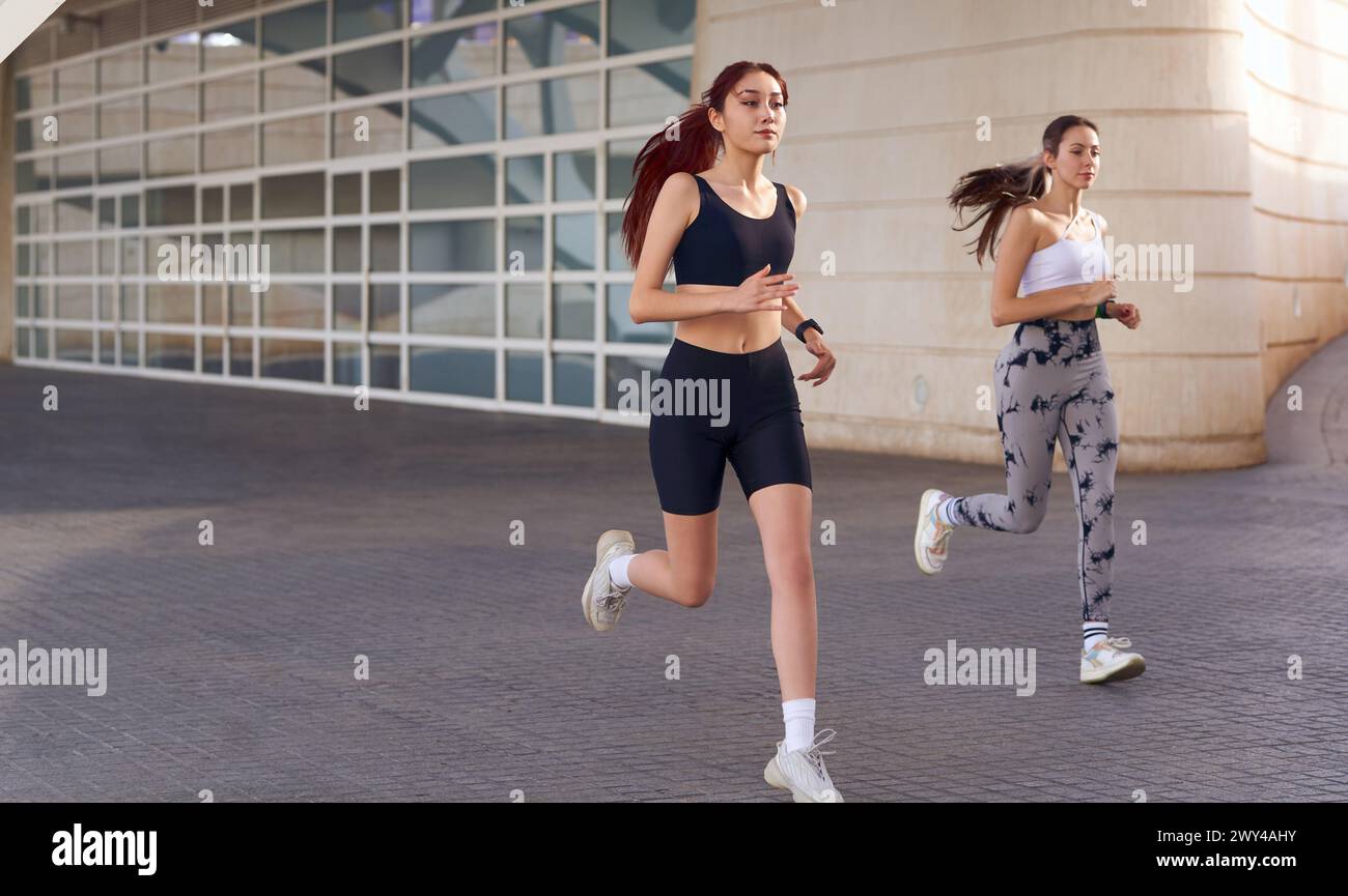 Active women athlete running on sunny morning side by side on modern ...